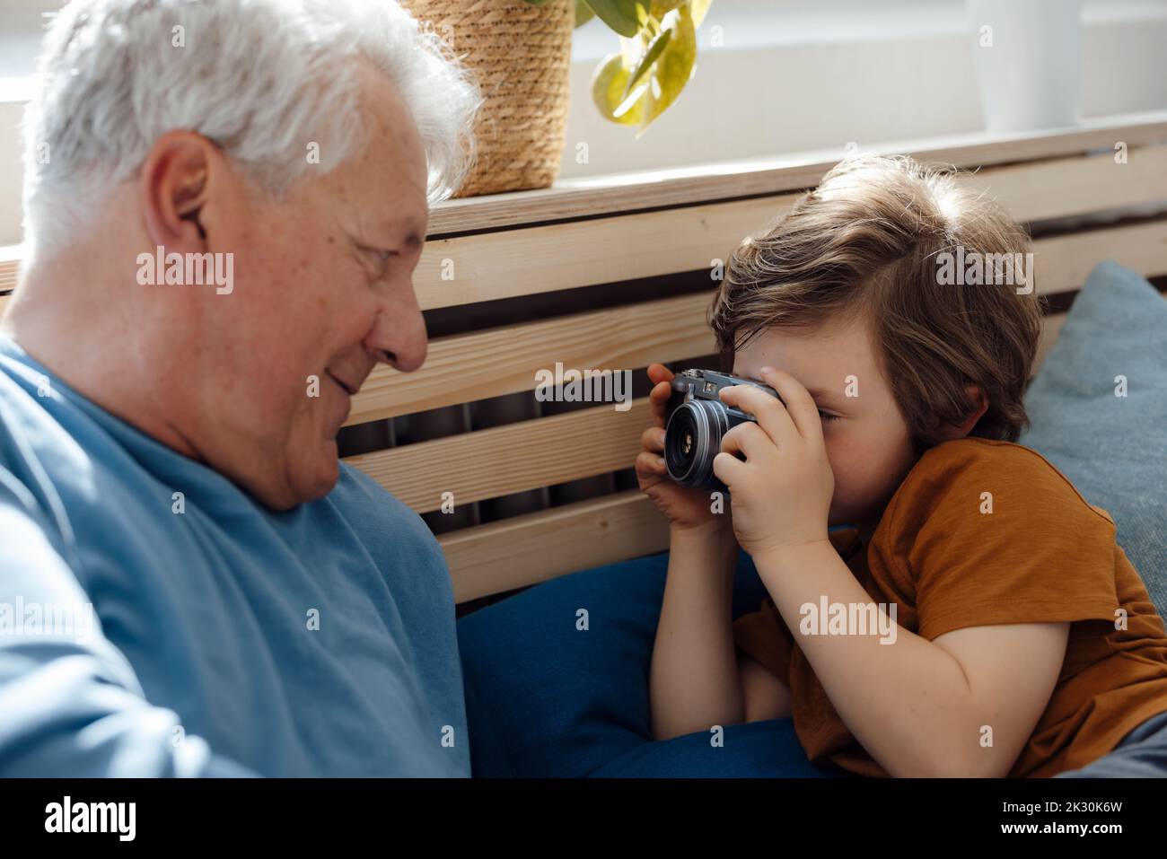 Grandson taking picture of grandfather through camera at home Stock ...