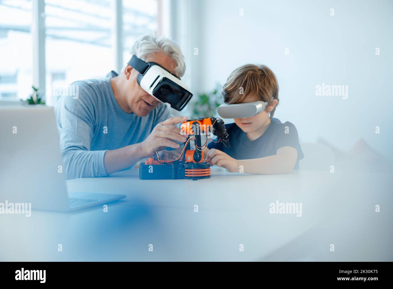 Grandfather and grandson with VR glasses watching robot model at home ...