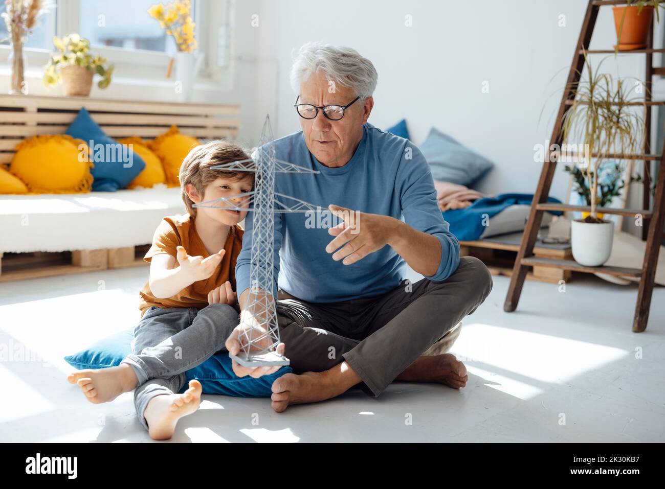 Grandson and grandfather examining electricity pylon model in living ...