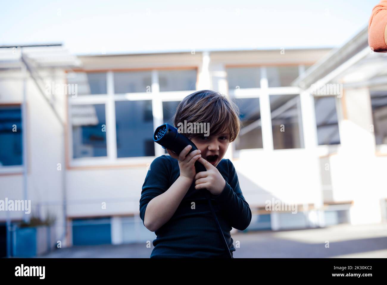 Playful boy holding electric charging plug Stock Photo - Alamy