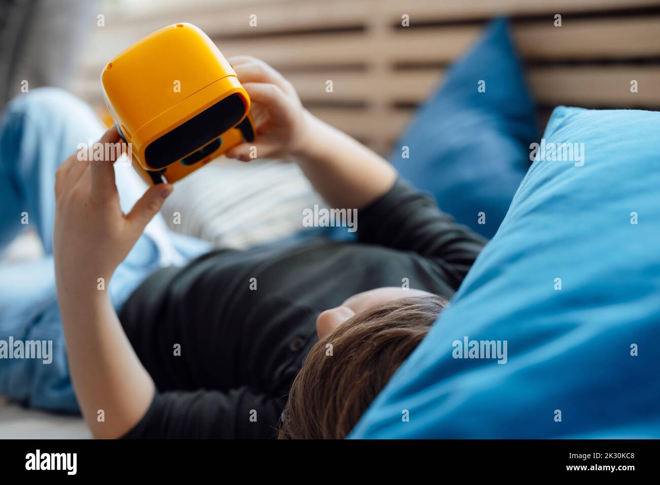 Boy holding AI toy robot lying down at home Stock Photo - Alamy