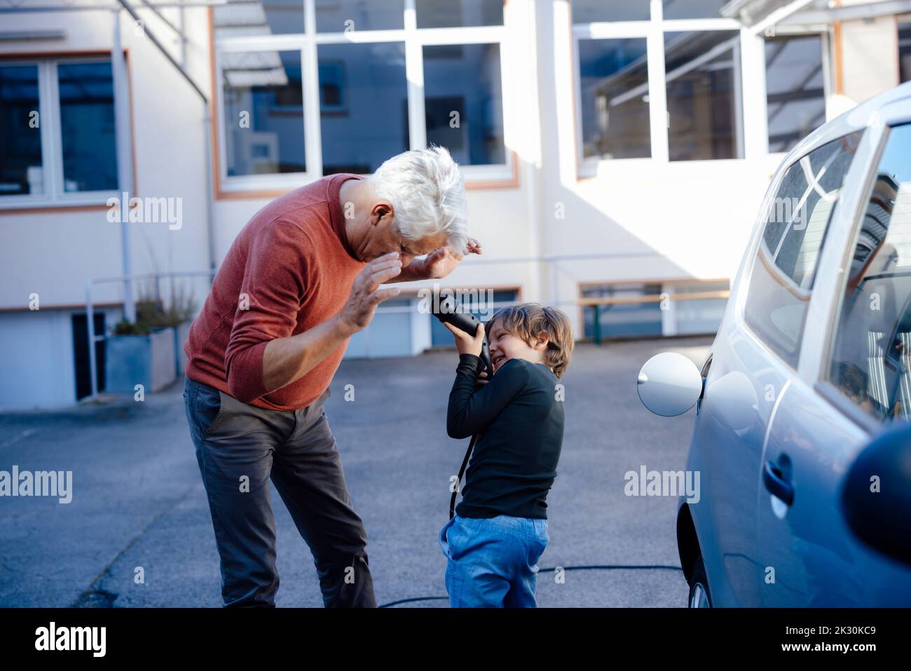Boy holding charging plug and playing with grandfather at station Stock ...