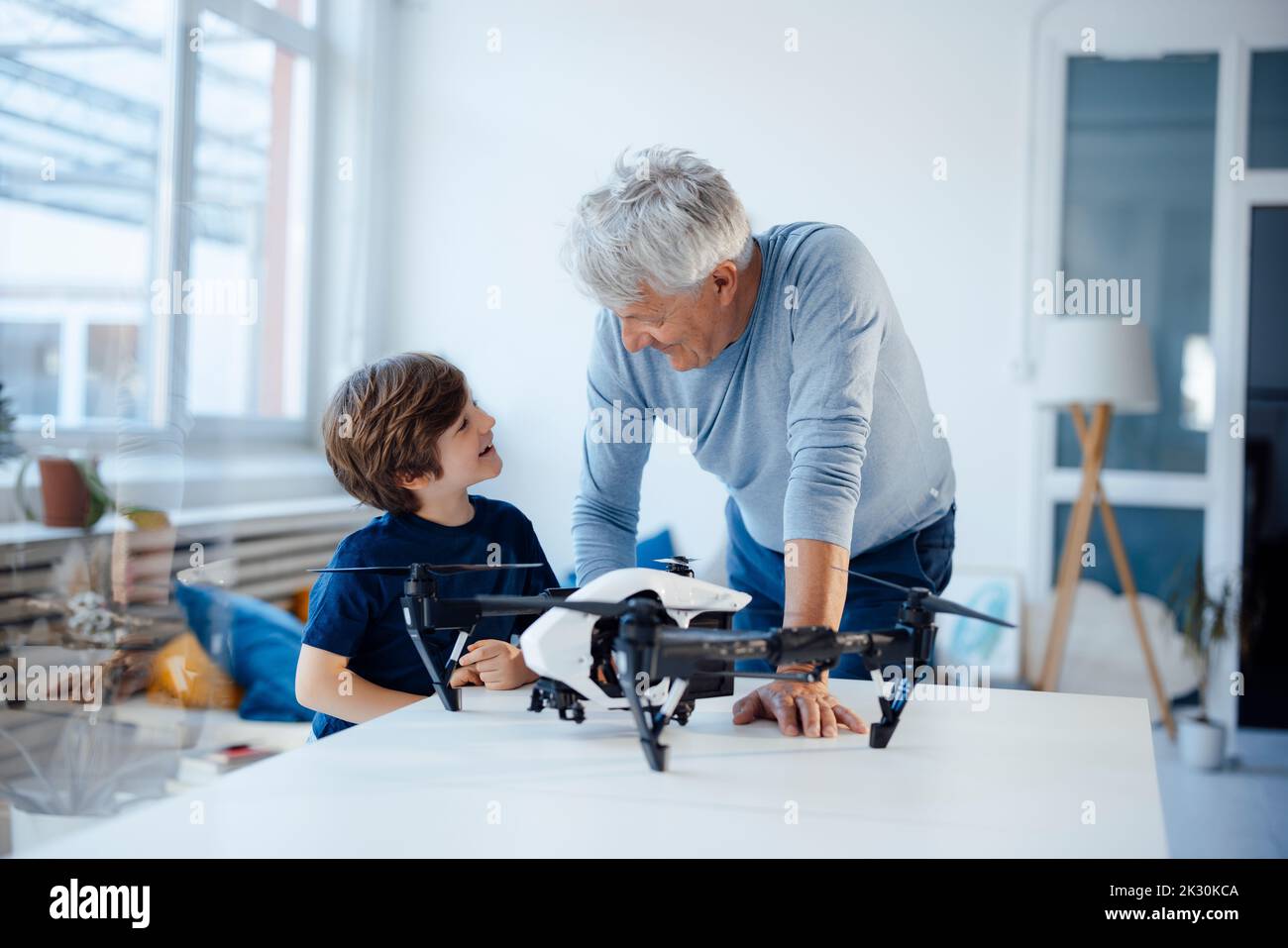 Grandfather and grandson talking with drone on table in living room ...