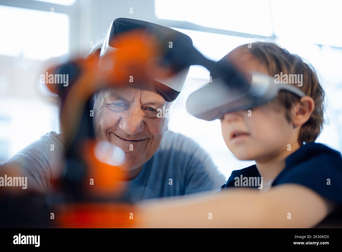 Smiling grandfather looking at robot model by grandson at home Stock ...