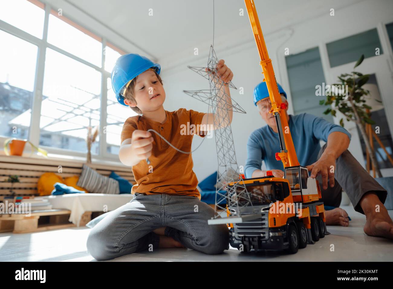 Boy imitating as engineer examining electricity pylon model with ...