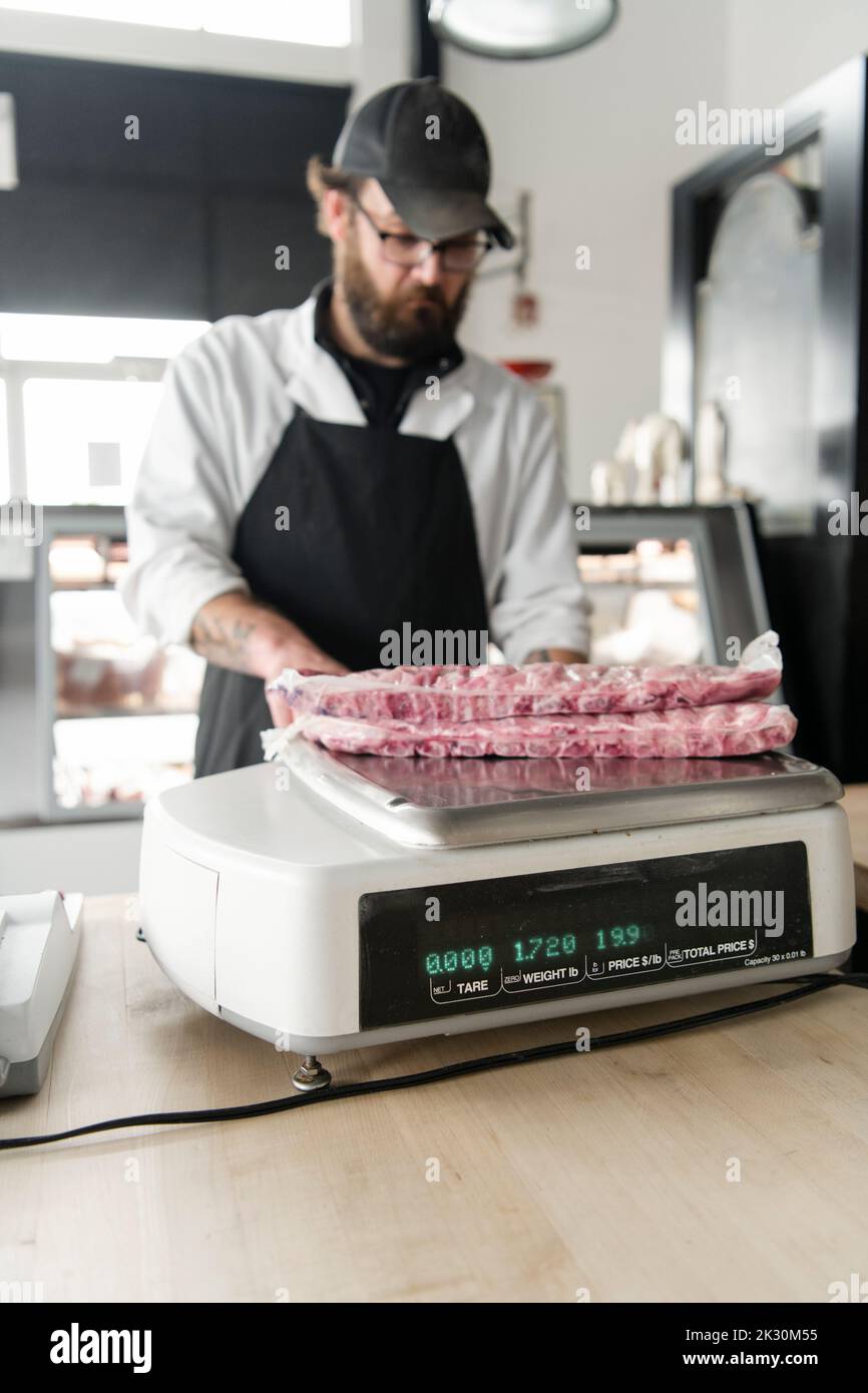 Butcher weighing meat behind counter Stock Photo - Alamy