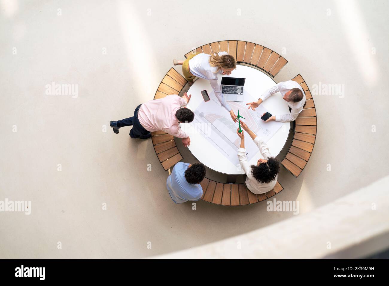Business colleagues planning over wind turbine sitting on table in ...