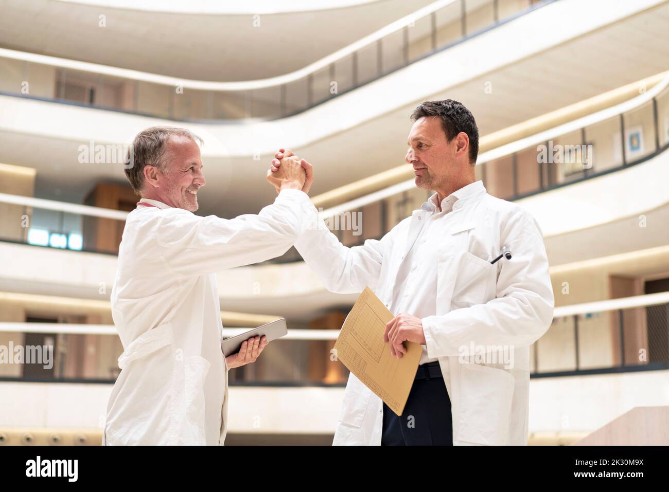 Doctors giving high-five to each other standing in hospital Stock Photo ...