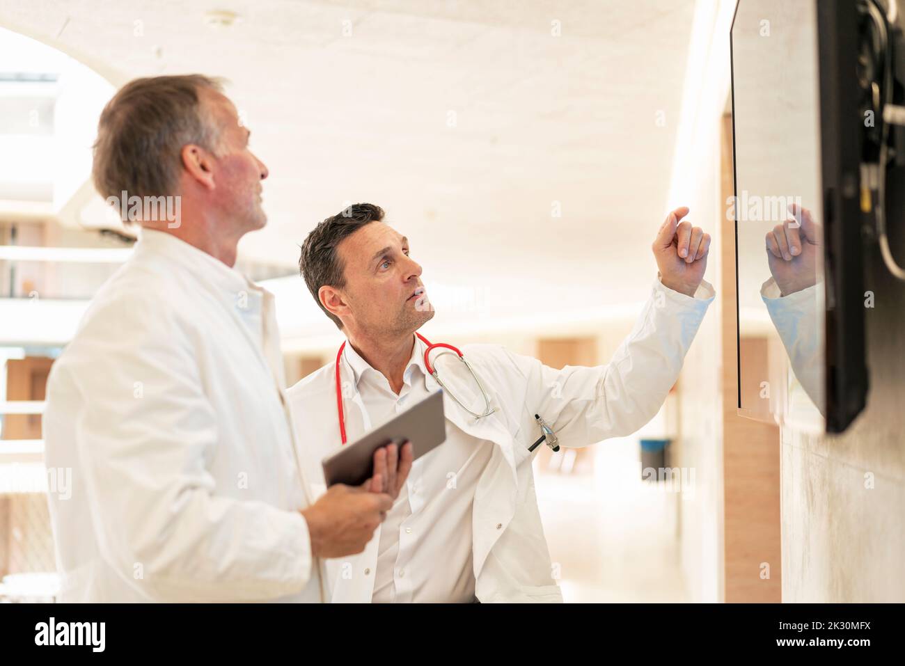 Doctor explaining colleague through screen on wall in hospital Stock ...