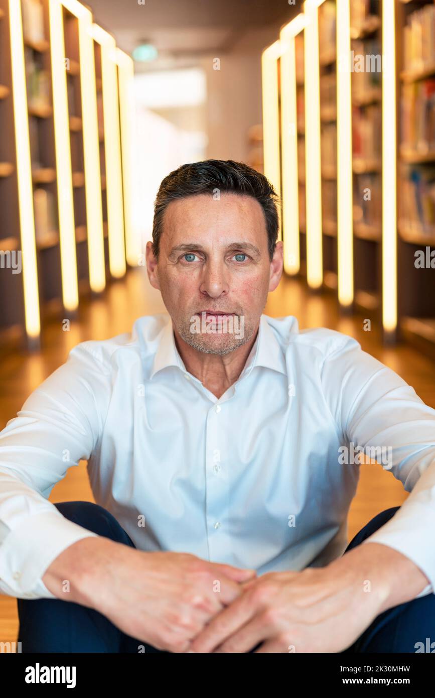 Man sitting in illuminated library at university Stock Photo - Alamy