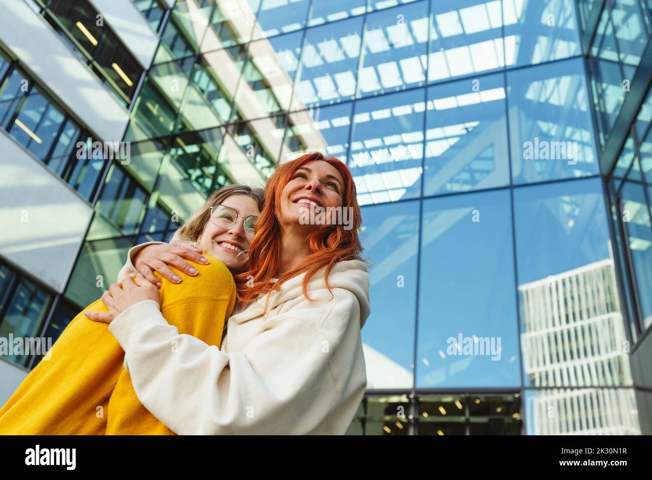 Happy redhead woman hugging daughter in front of building Stock Photo ...