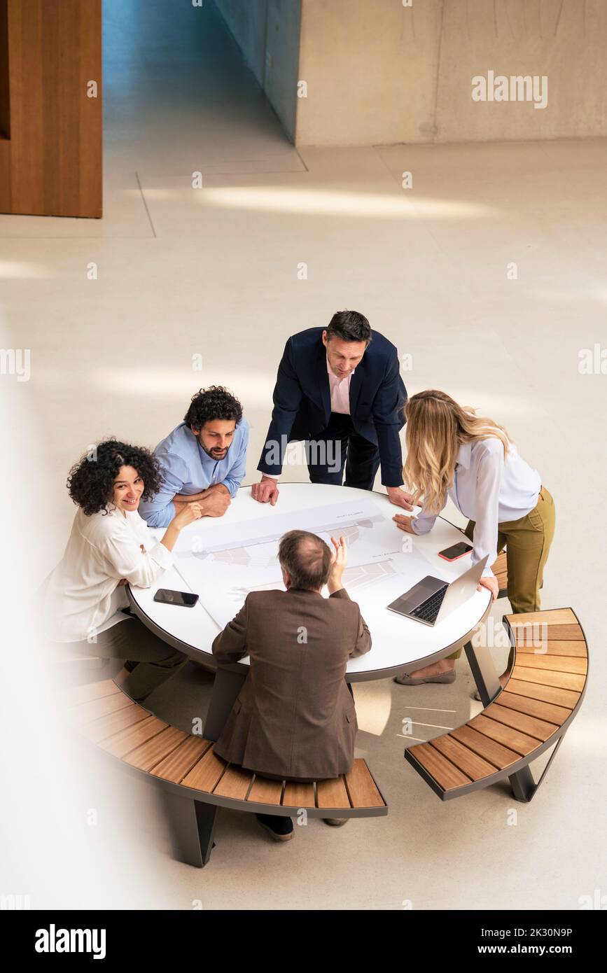 Multiracial business colleagues planning strategy at table in corridor ...