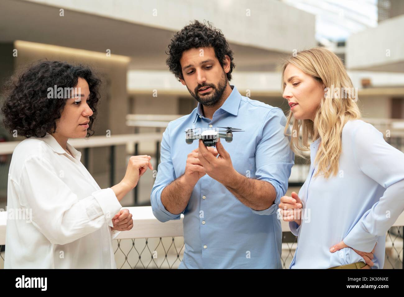 Multiracial colleagues discussing over drone in office corridor Stock Photo - Alamy