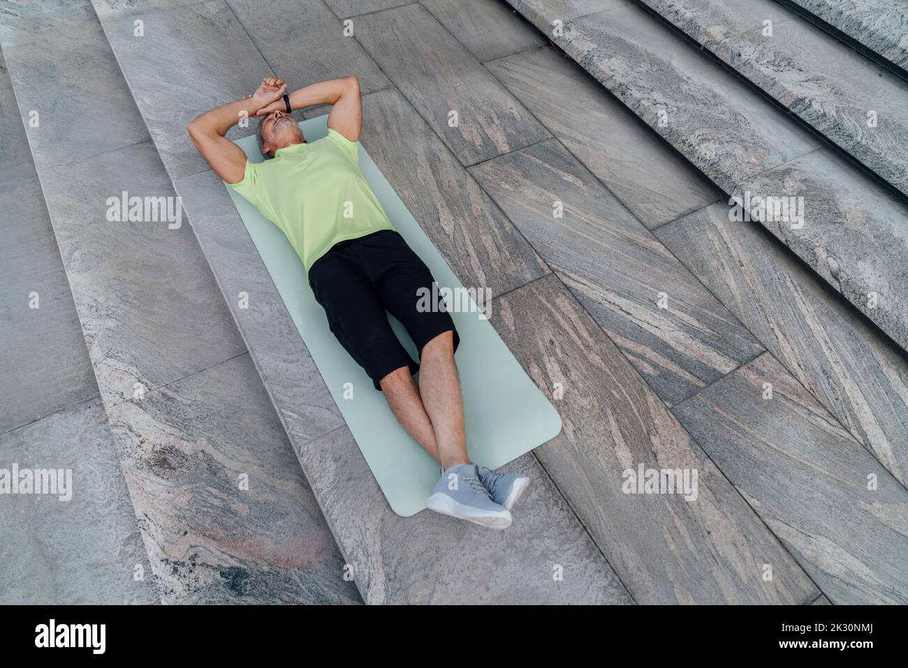 Exhausted man lying on exercise mat near steps Stock Photo - Alamy