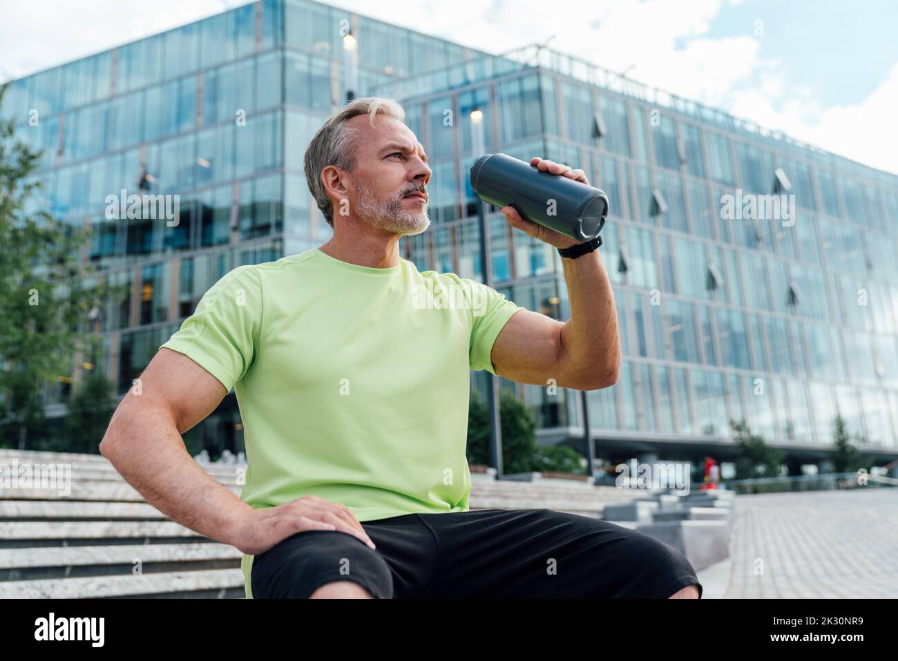 Man drinking water sitting in front of building Stock Photo - Alamy