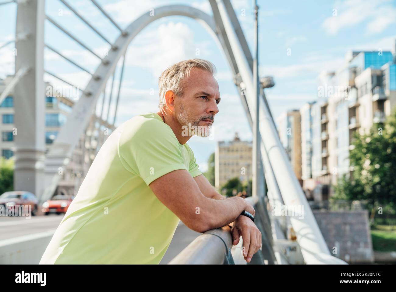Thoughtful man leaning on railing of bridge Stock Photo - Alamy