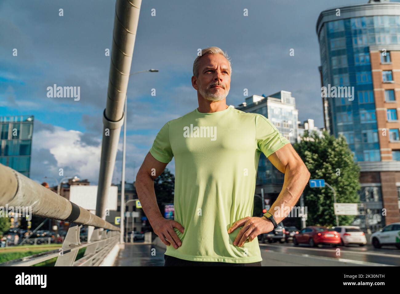 Thoughtful man with hands on hips standing by railing Stock Photo - Alamy