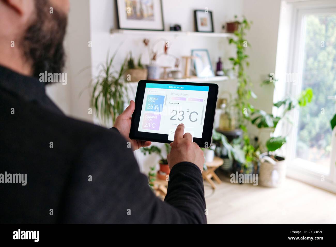 Man adjusting temperature of room through tablet PC at home Stock Photo ...