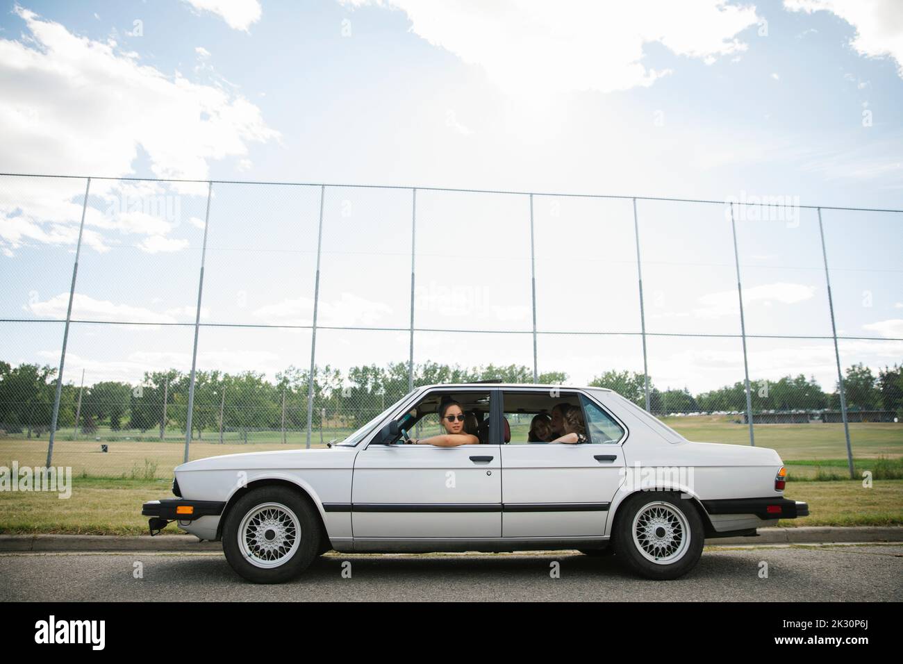 Teenage girl friends in car parked outside high school baseball field ...