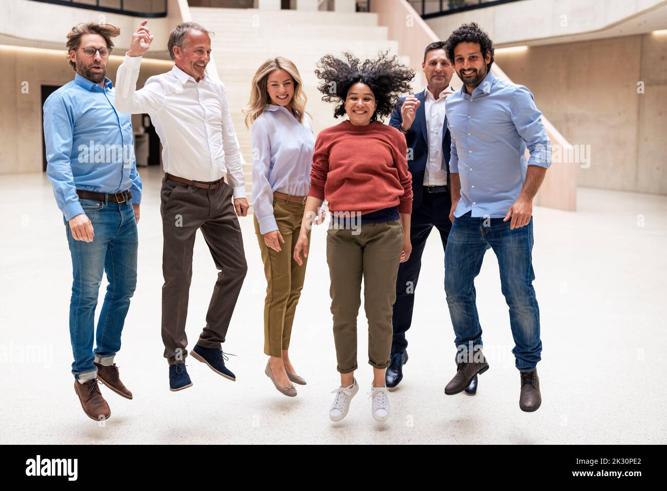 Cheerful business colleagues jumping in office lobby Stock Photo - Alamy