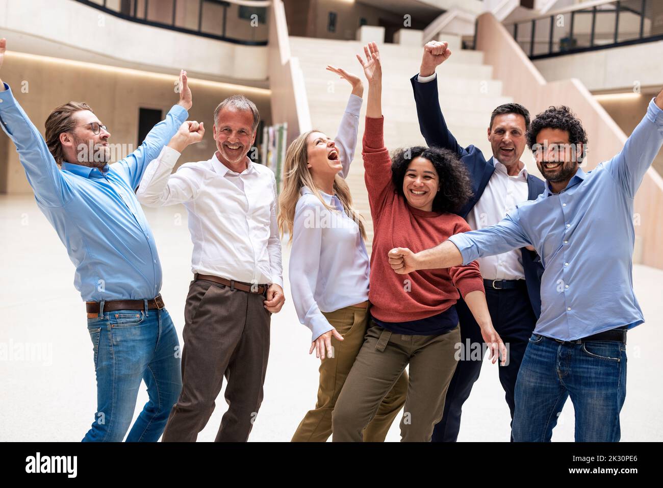 Cheerful multiracial business colleagues celebrating success in lobby ...
