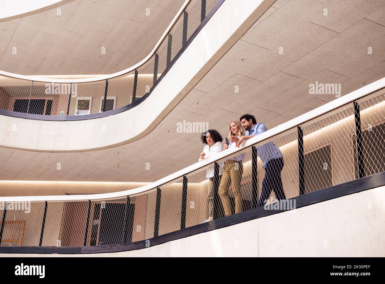 Business colleagues leaning on railing in corridor Stock Photo - Alamy