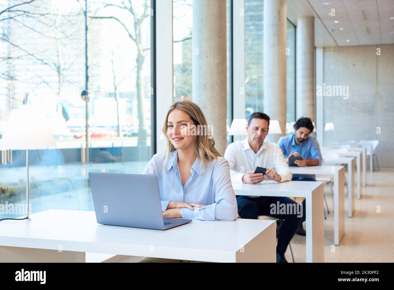 Smiling teacher with laptop on desk in university Stock Photo - Alamy