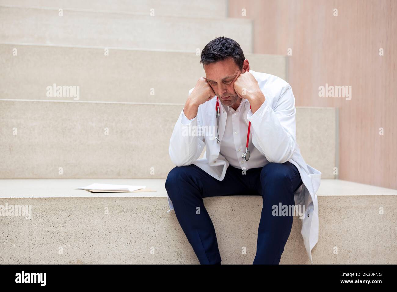 Tired mature doctor napping on steps in hospital Stock Photo - Alamy