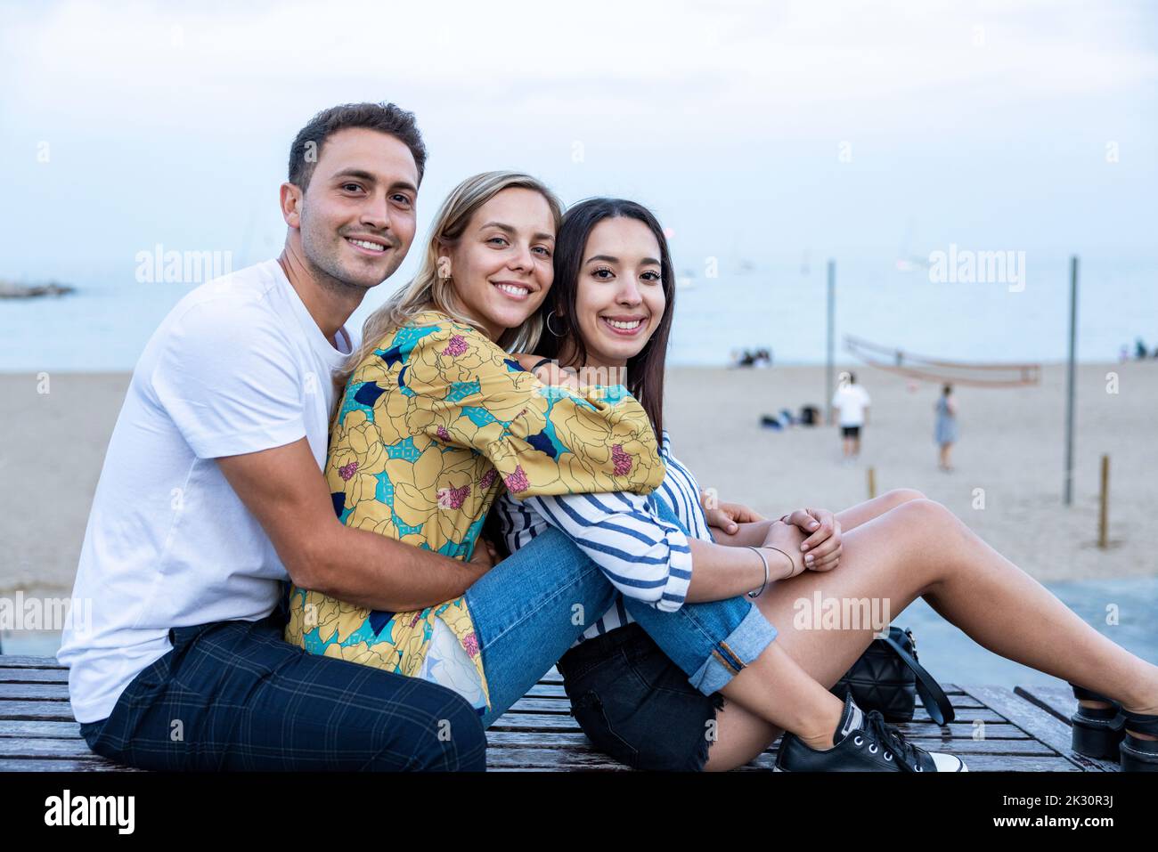 Happy friends sitting together at promenade Stock Photo - Alamy