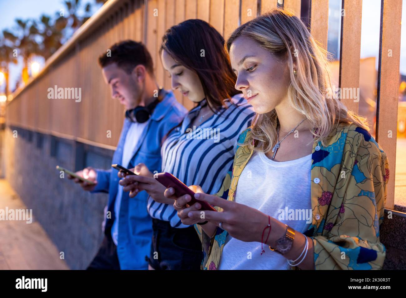 Young women and man surfing net through smart phones in front of ...