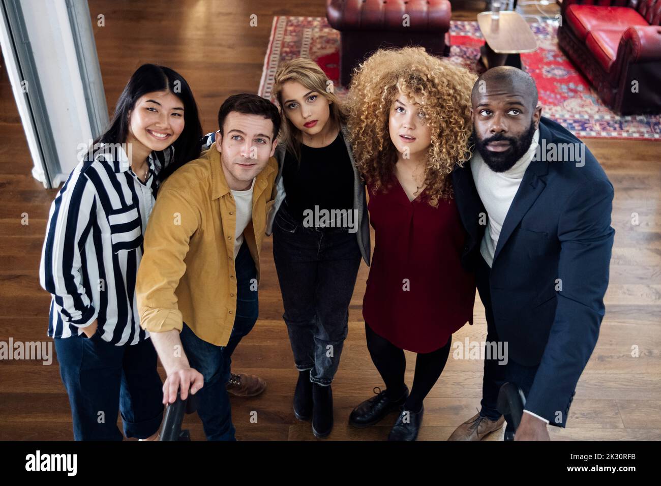 Curious young business people standing in office looking up Stock Photo ...