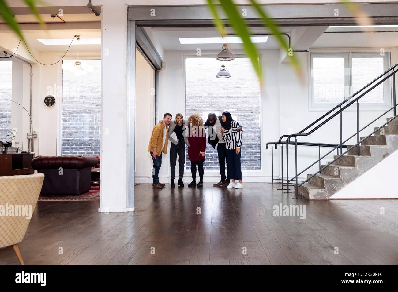 Business people standing in modern office with arms around Stock Photo ...