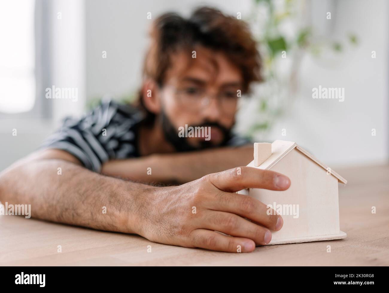 Man with small model house sitting at home Stock Photo - Alamy