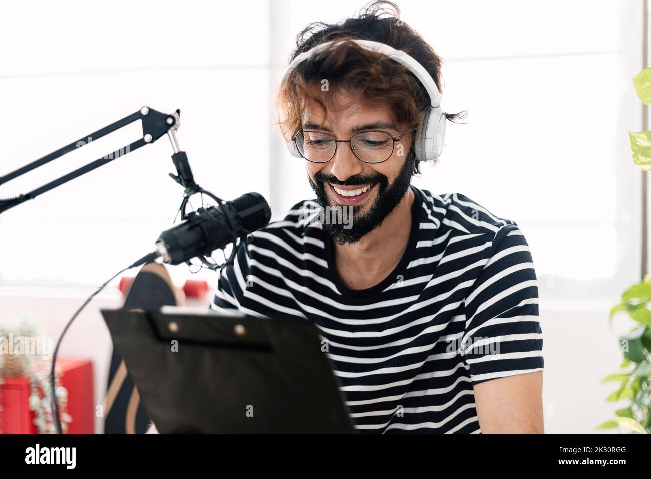 Happy man reading script and recording through microphone at home ...