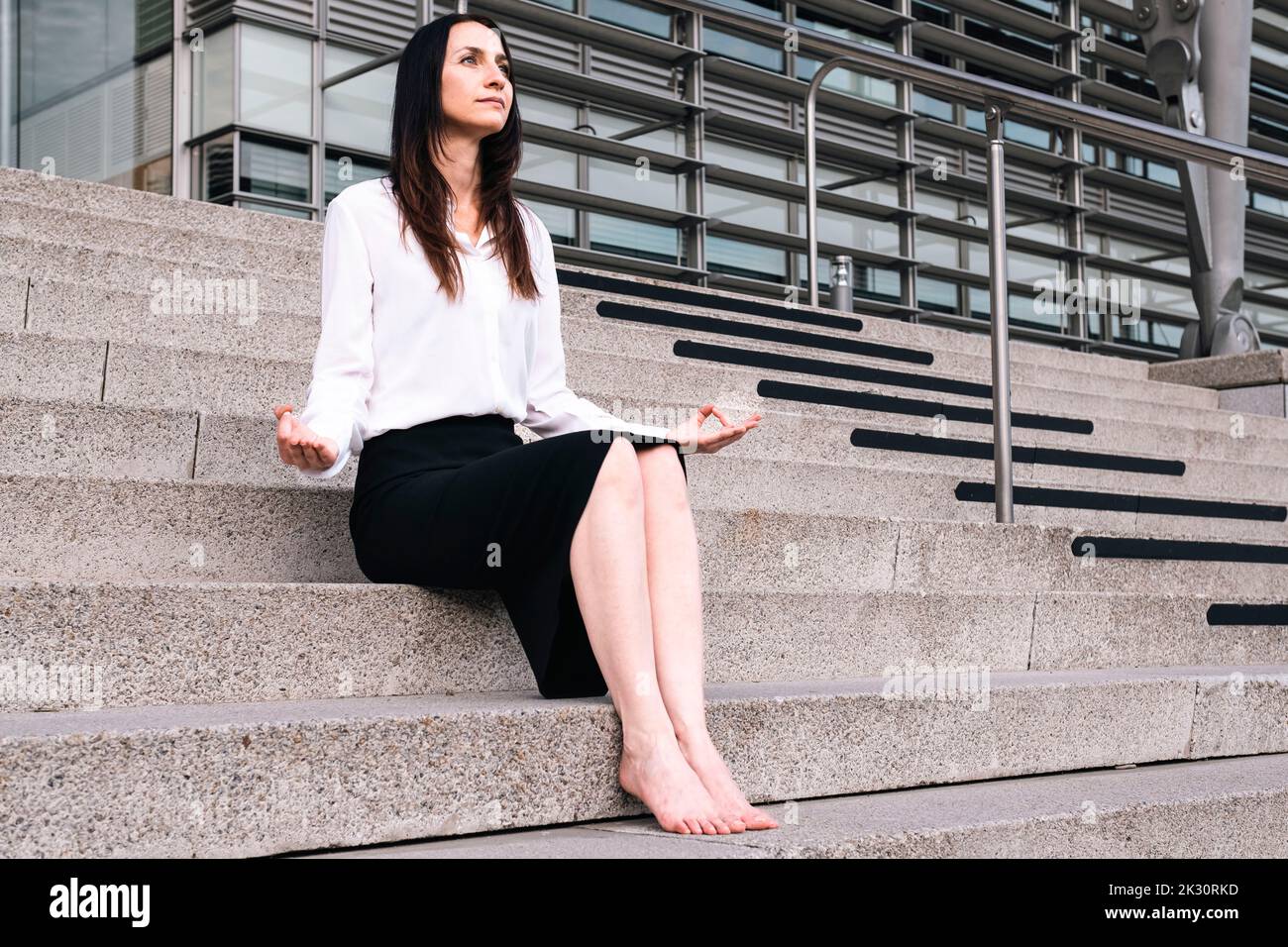 Contemplative woman sitting on staircase doing meditation outside ...