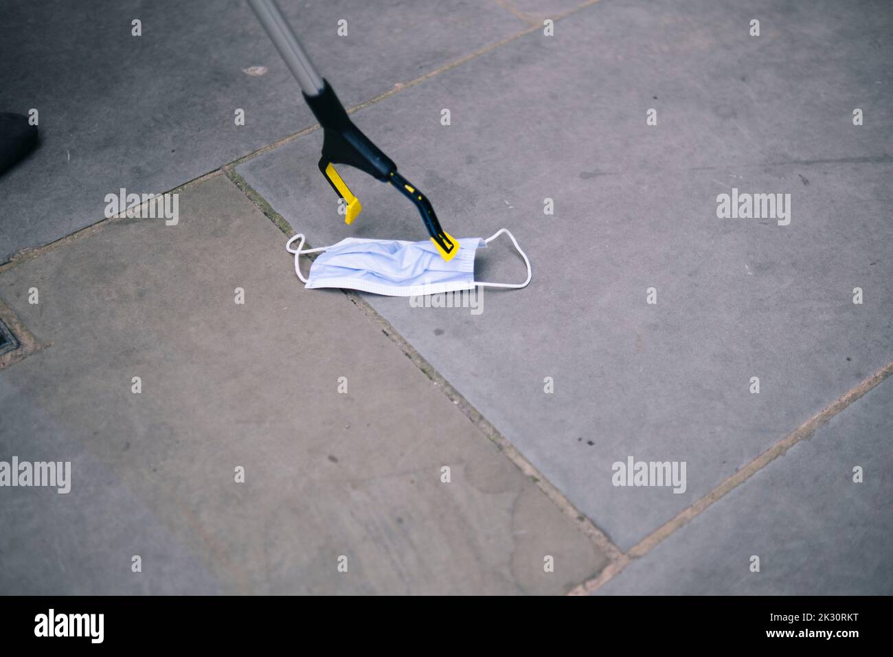 Protective face mask litter and waste picker on footpath Stock Photo ...