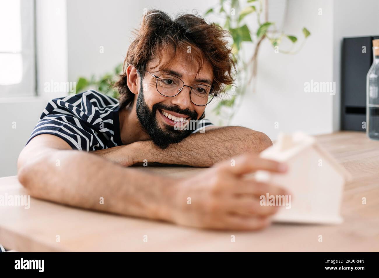 Happy man with small house model at home Stock Photo - Alamy