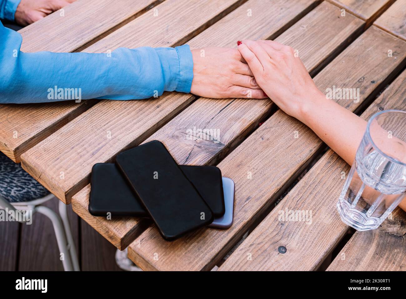 Colleague touching hand by stack of smart phones on table at restaurant ...