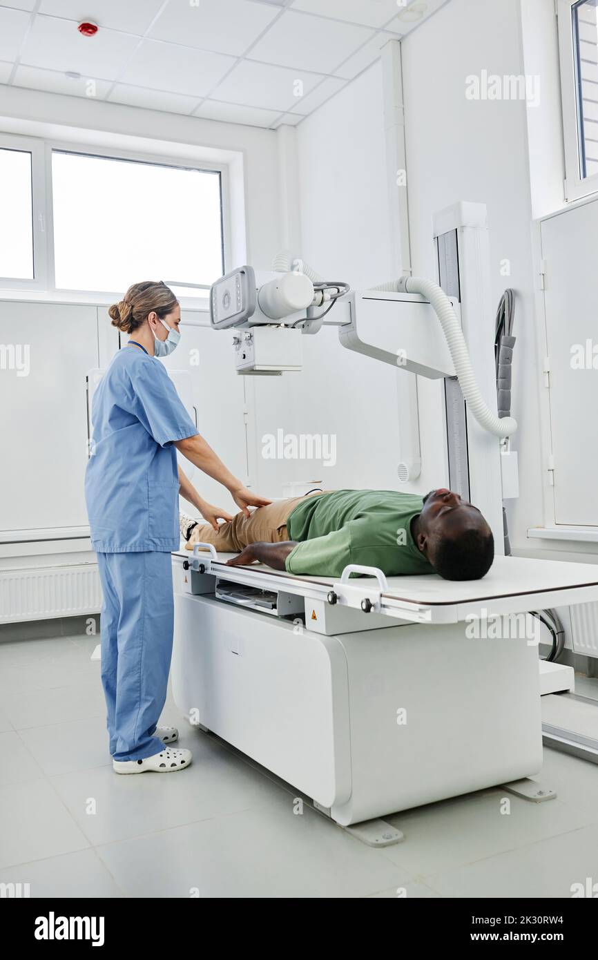 Nurse wearing scrubs taking X-ray shot of patient in clinic Stock Photo ...