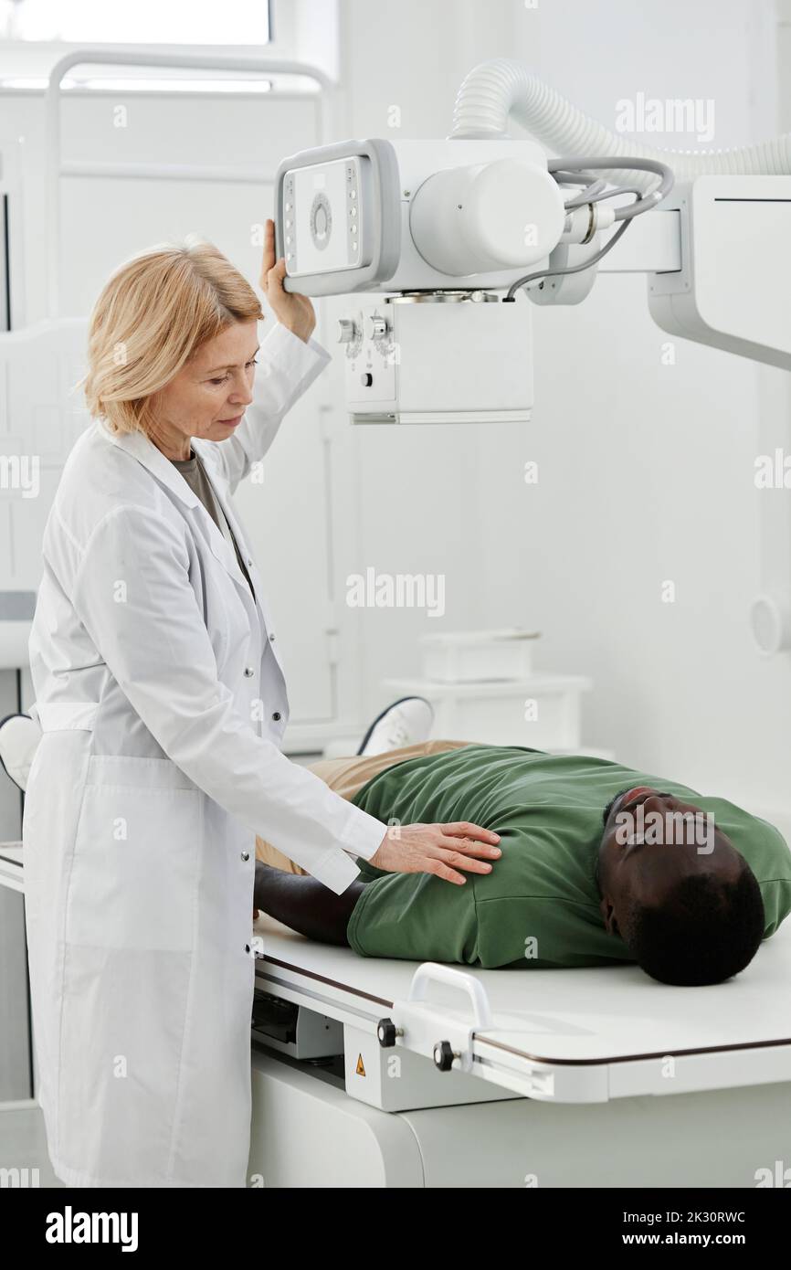 Doctor instructing patient lying on X-ray machine in clinic Stock Photo ...