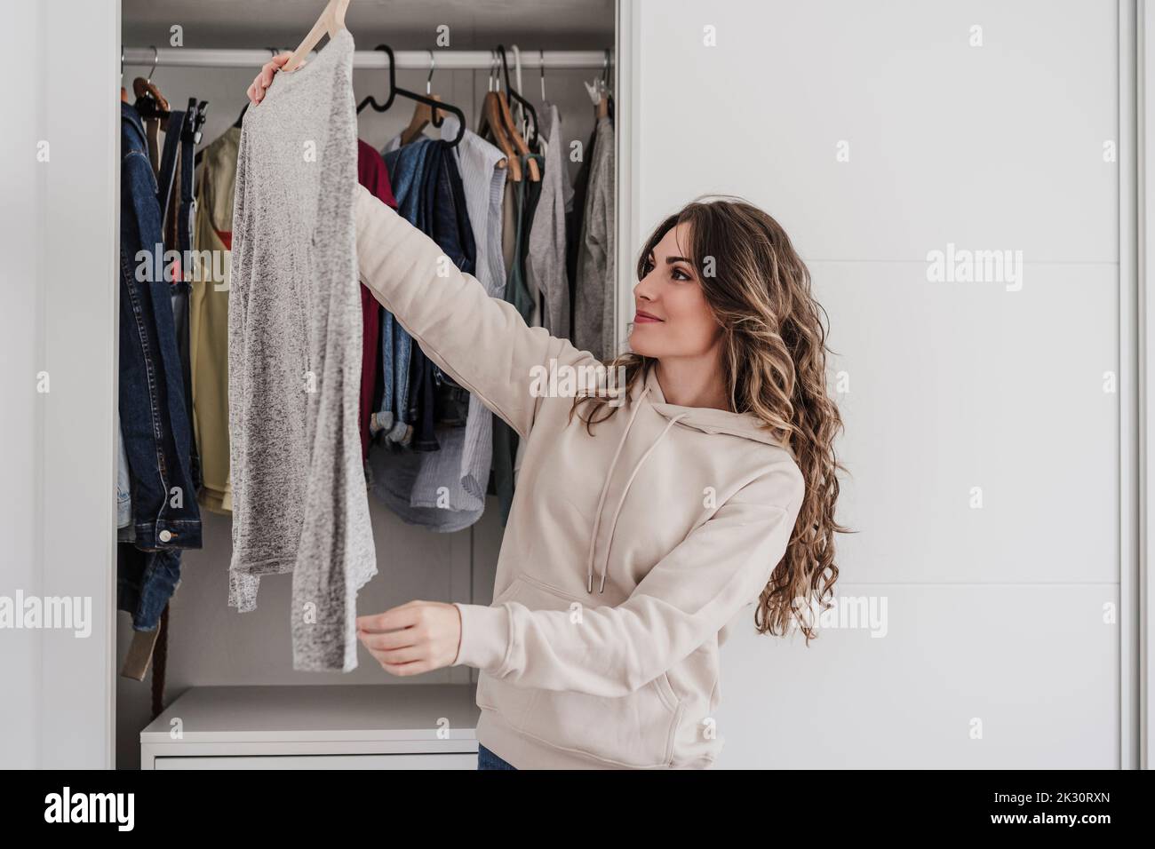 Young woman picking outfit from closet at home Stock Photo - Alamy
