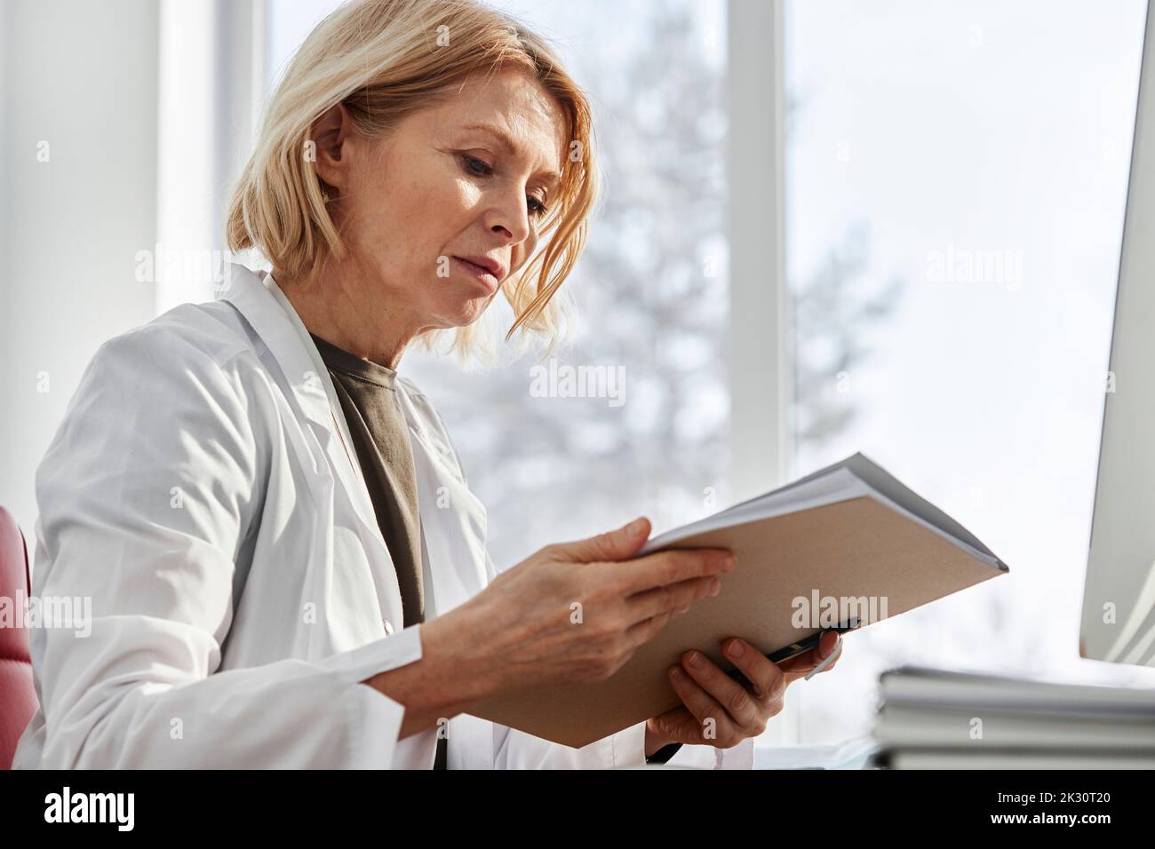 Doctor examining medical report in clinic Stock Photo - Alamy
