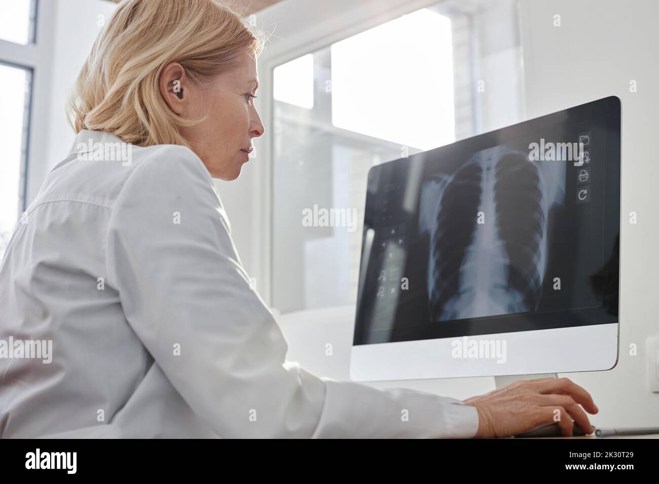 Doctor analyzing X-ray image on desktop PC in clinic Stock Photo - Alamy