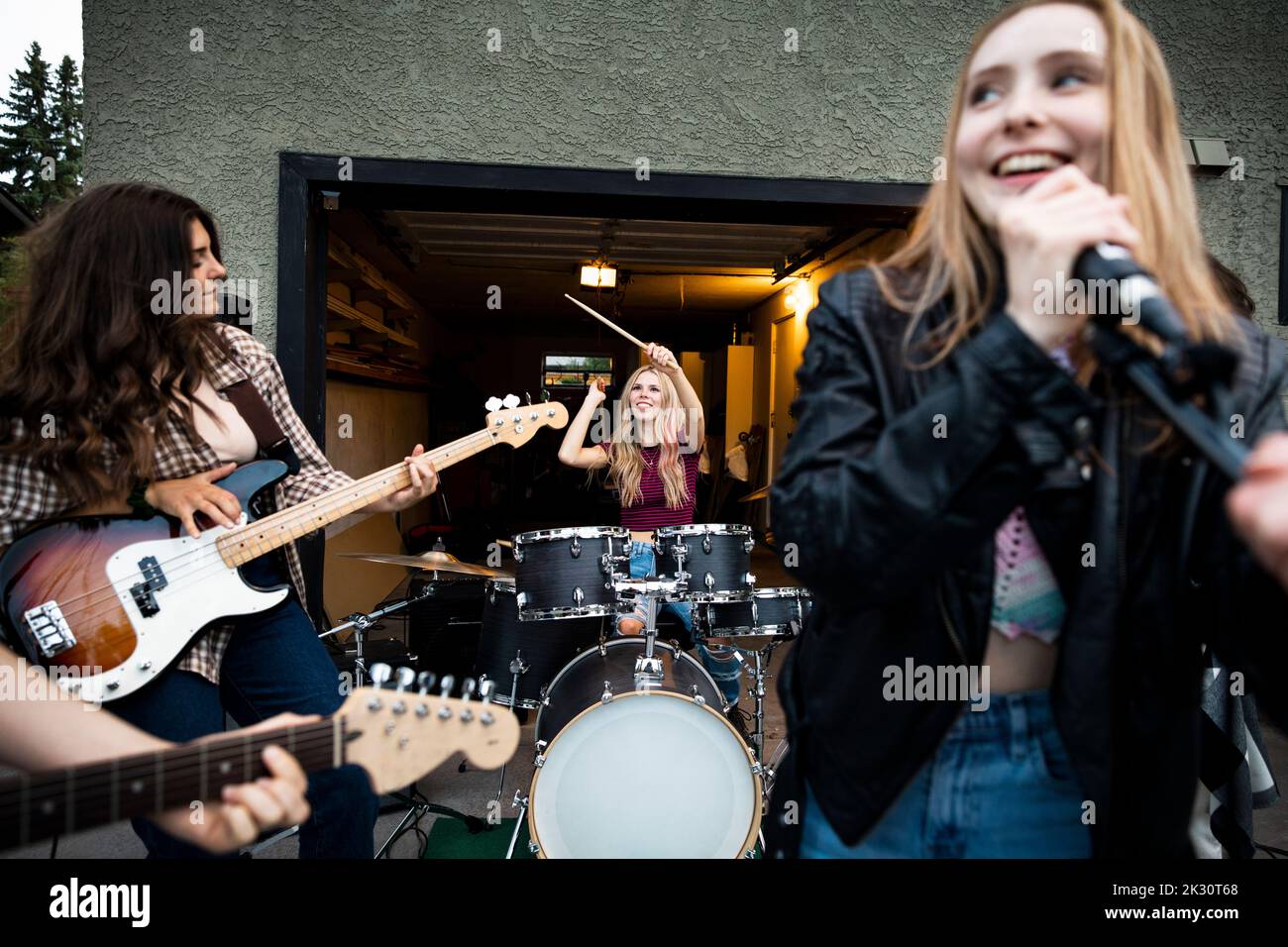 Teenage girl friend rock band singing and playing music in driveway ...