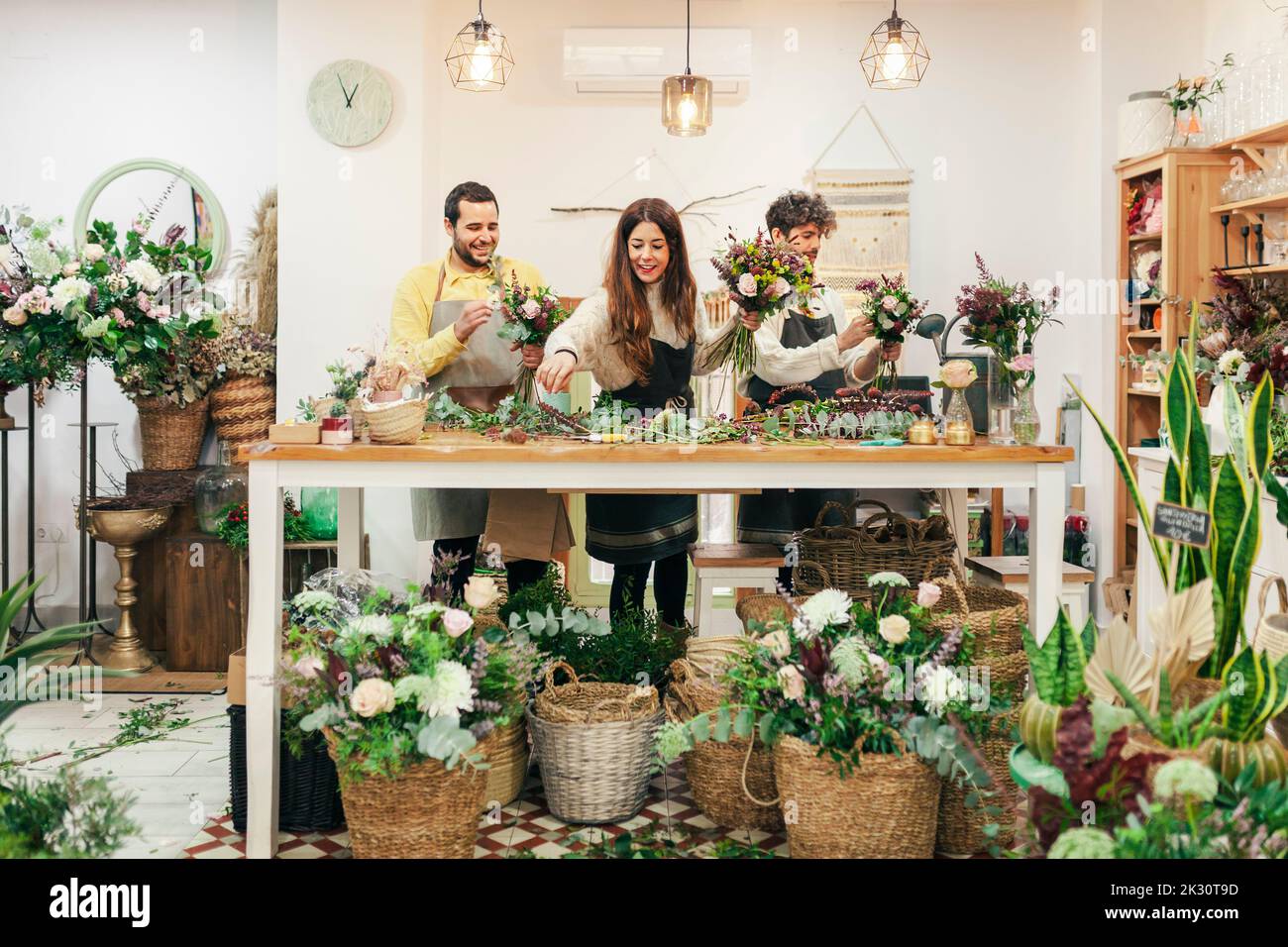 Colleagues making bouquet standing by workbench at flower shop Stock ...