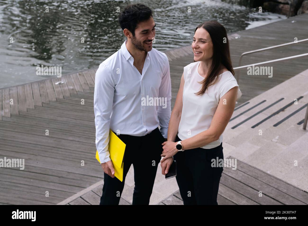 Happy colleagues talking with each other standing on steps at office ...