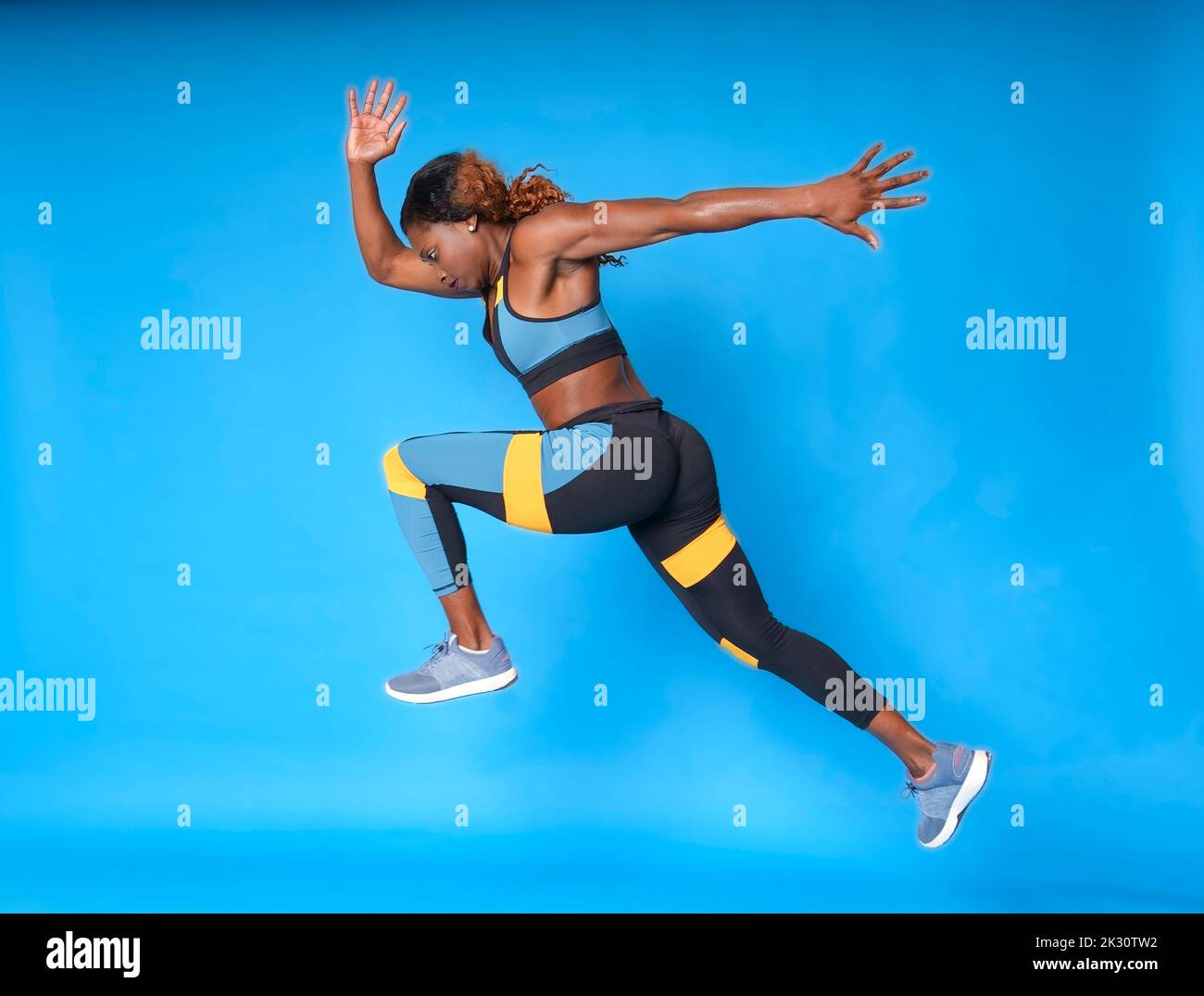 Determined woman running against blue background Stock Photo - Alamy