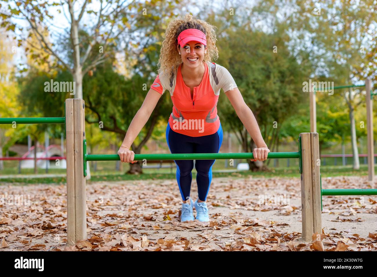 Happy sportswoman practicing push-ups on horizontal bar at park Stock ...