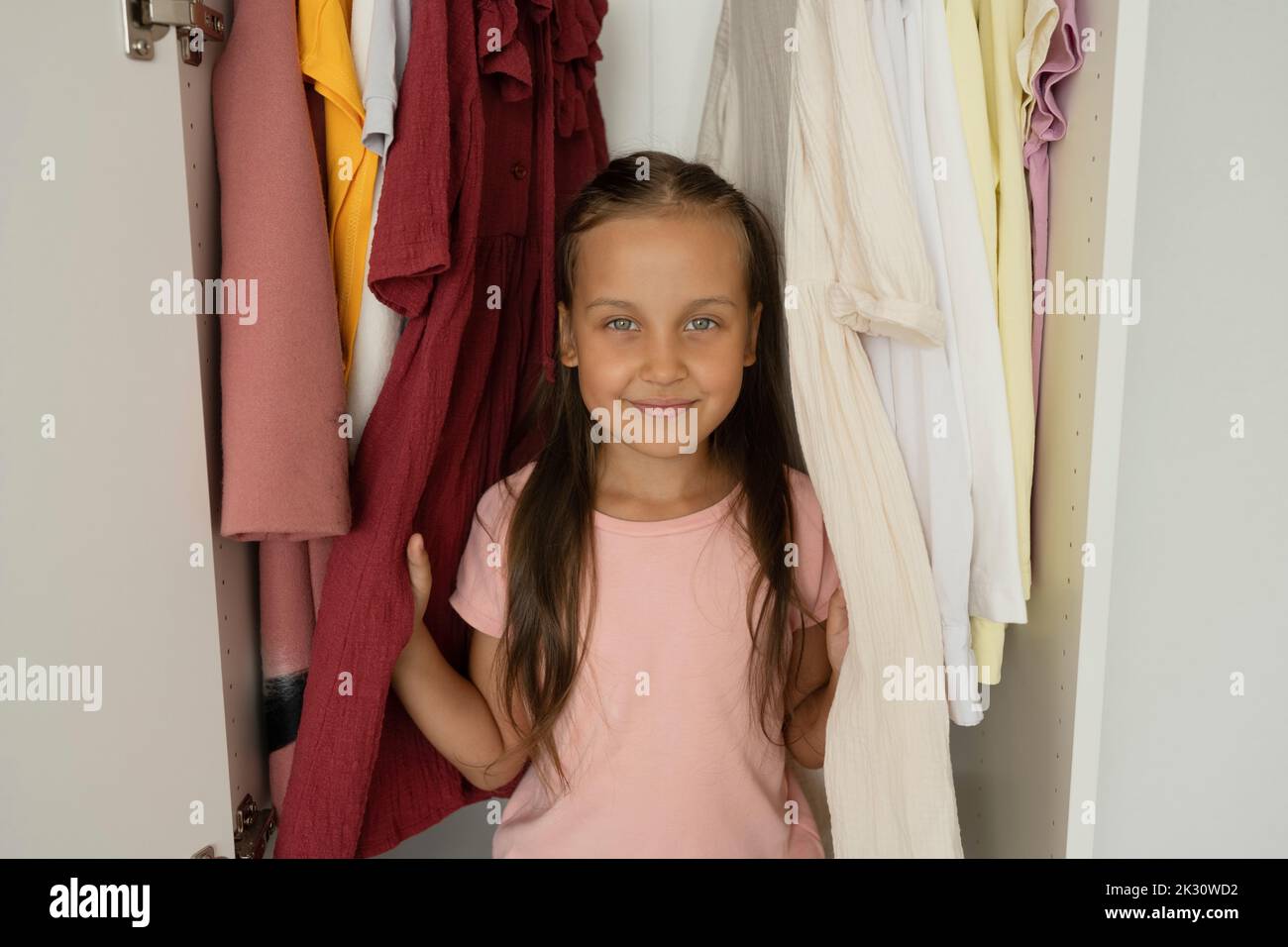 Girl with eyes closed sitting by clothes in closet Stock Photo - Alamy