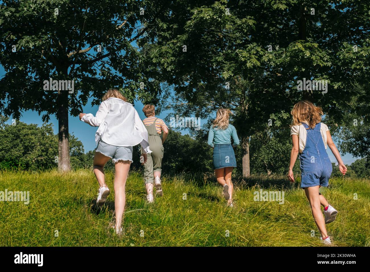 Friends running together towards trees at park Stock Photo - Alamy